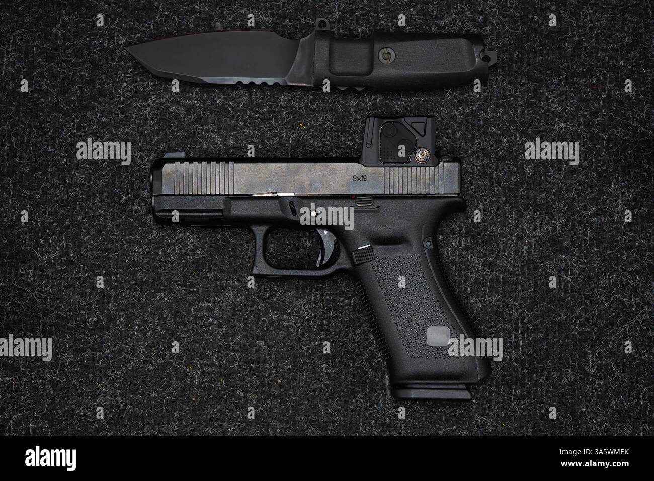 Modern tactical 9mm pistol with a collimator sight and a sharp knife ...