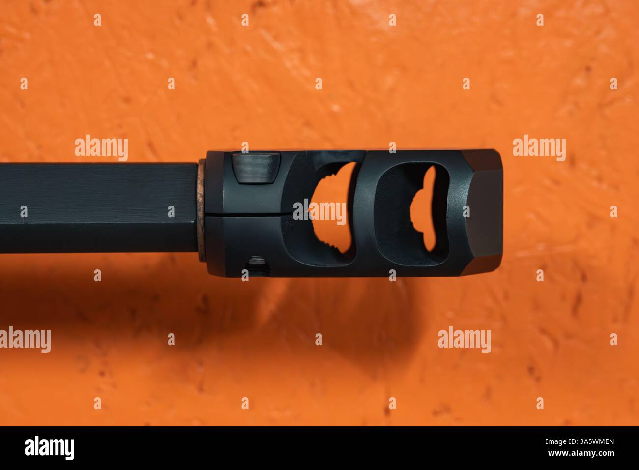 Large muzzle brake compensator on the rifle barrel on orange background ...