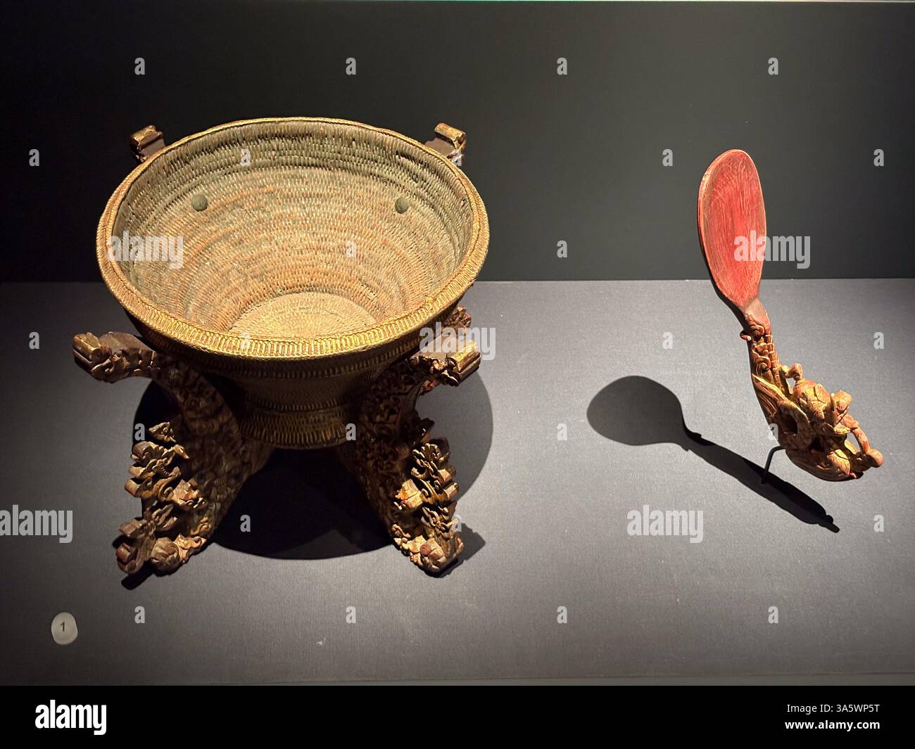 A display of cultural objects - an ornate woven basket and a red ...
