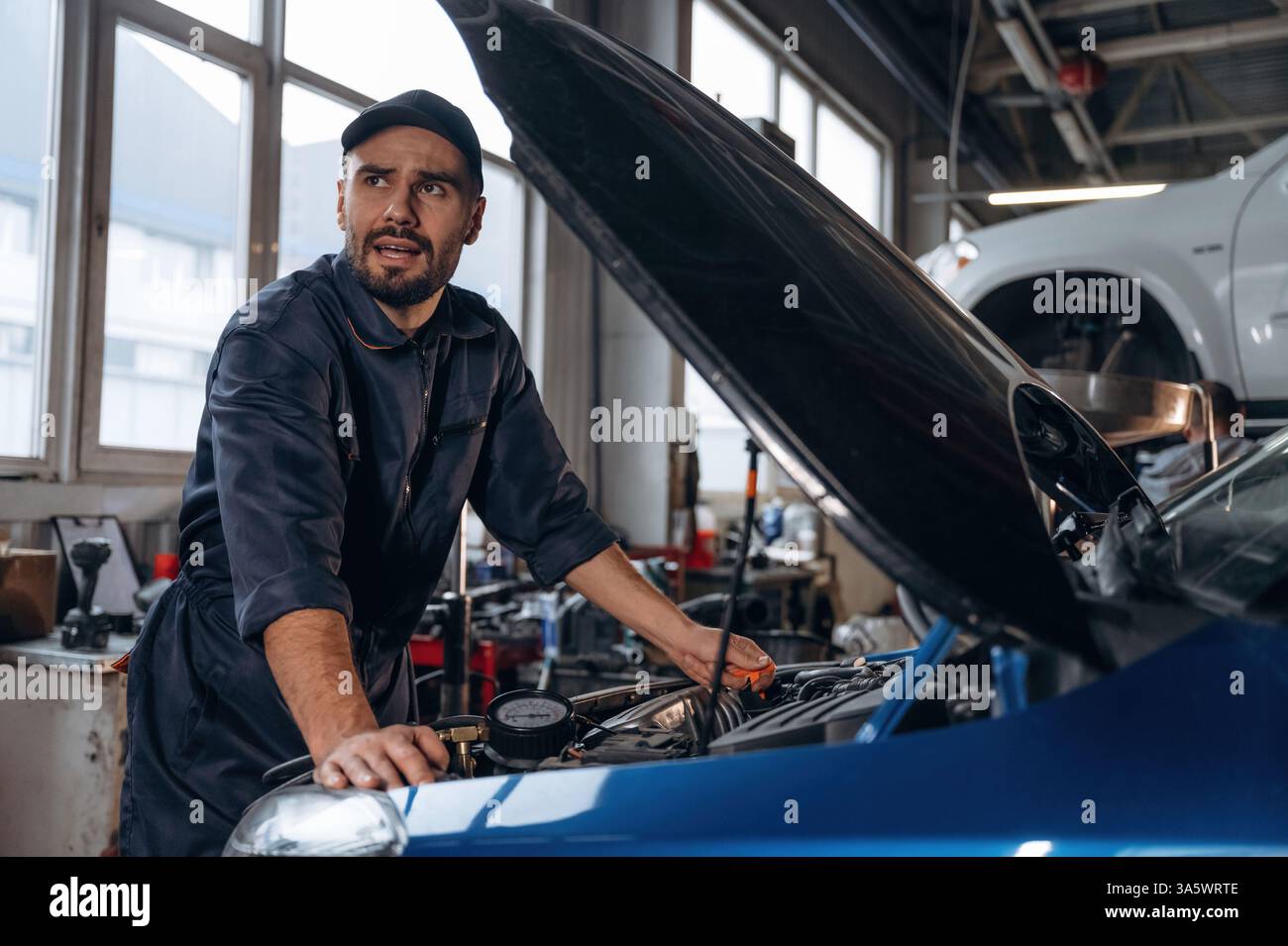 In the cap, busy. Mechanic working in a car service station Stock Photo ...