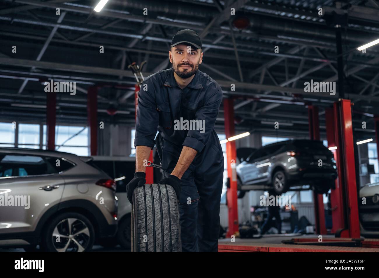 Moving the tire. Mechanic working in a car service station Stock Photo ...