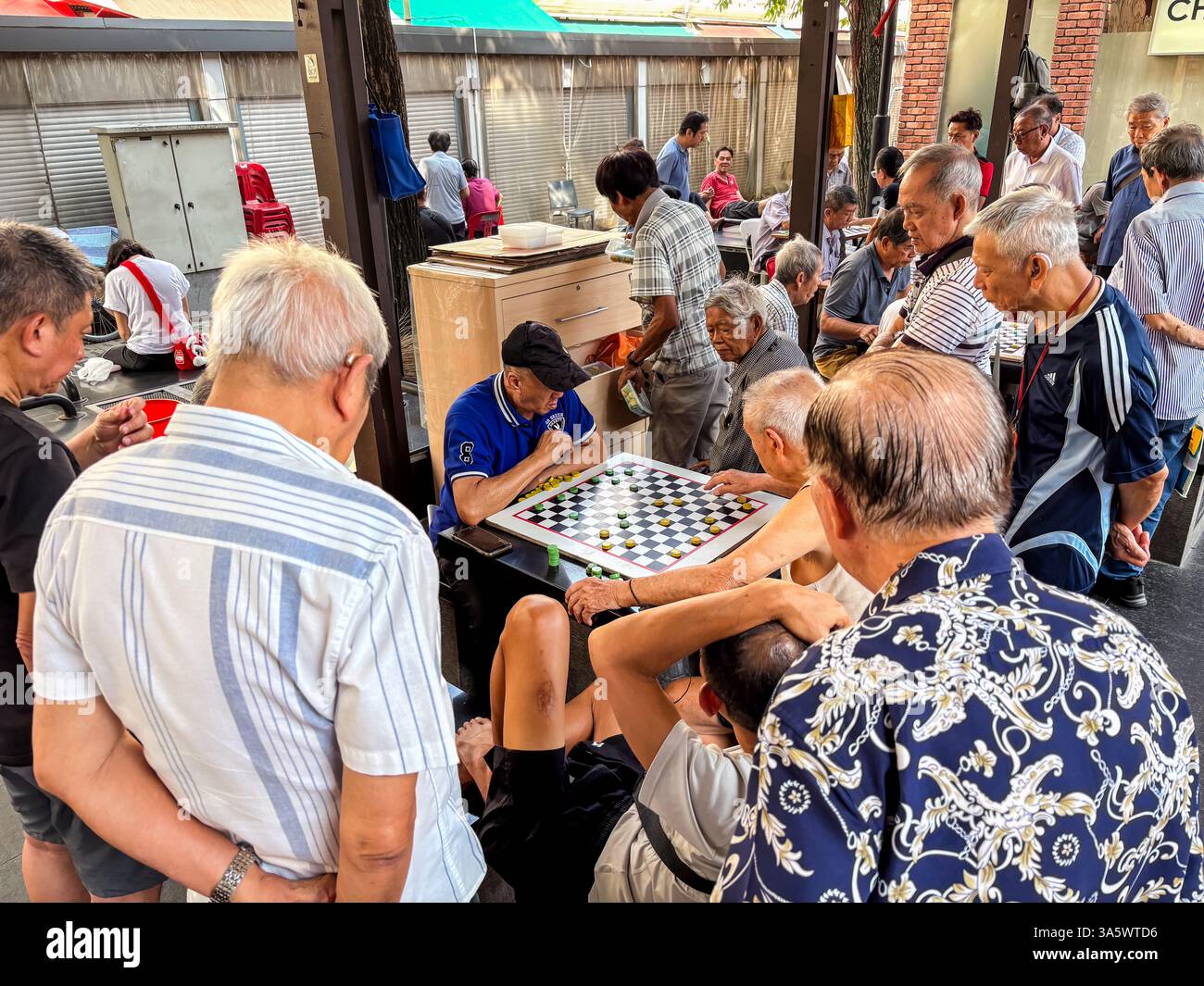 Group of senior men playing checkers in a public space in Singapore ...