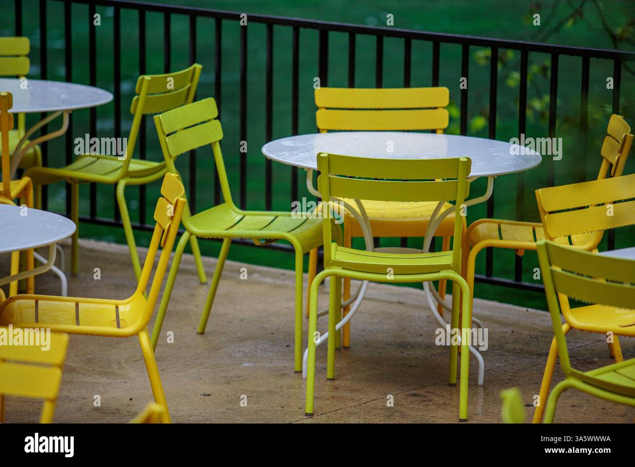 A quiet outdoor café with empty metal chairs and tables under the ...