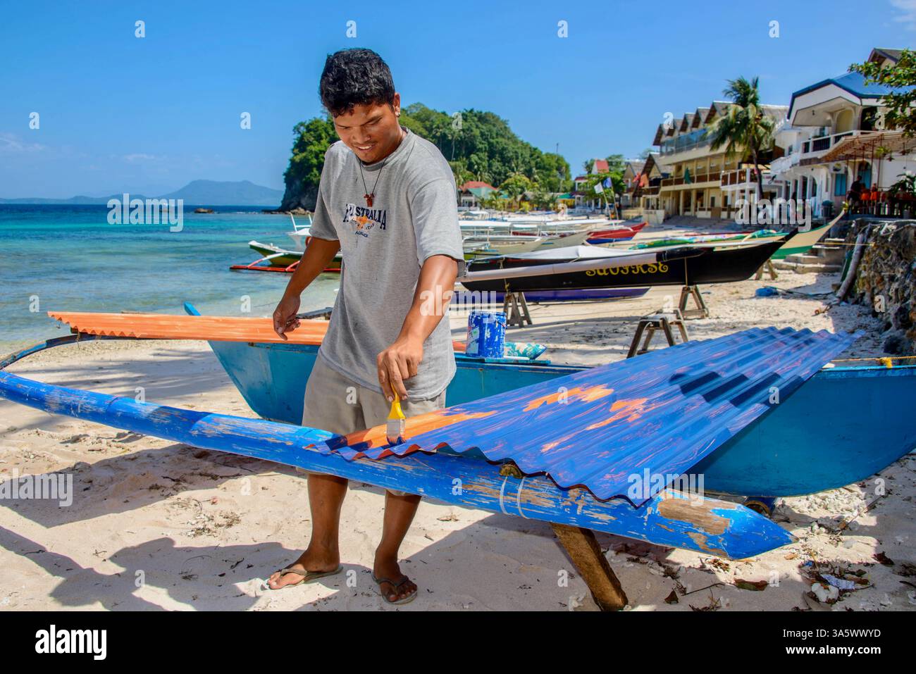 A fisherman paints his fishing boat on Big La Laguna Beach in PUERTO ...