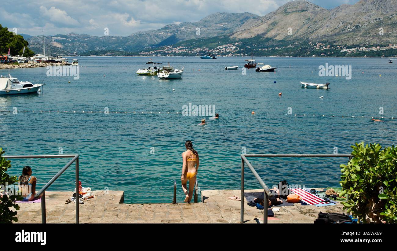 Scenic Beachfront with Swimmers, Boats, and Mountains in Relaxing ...