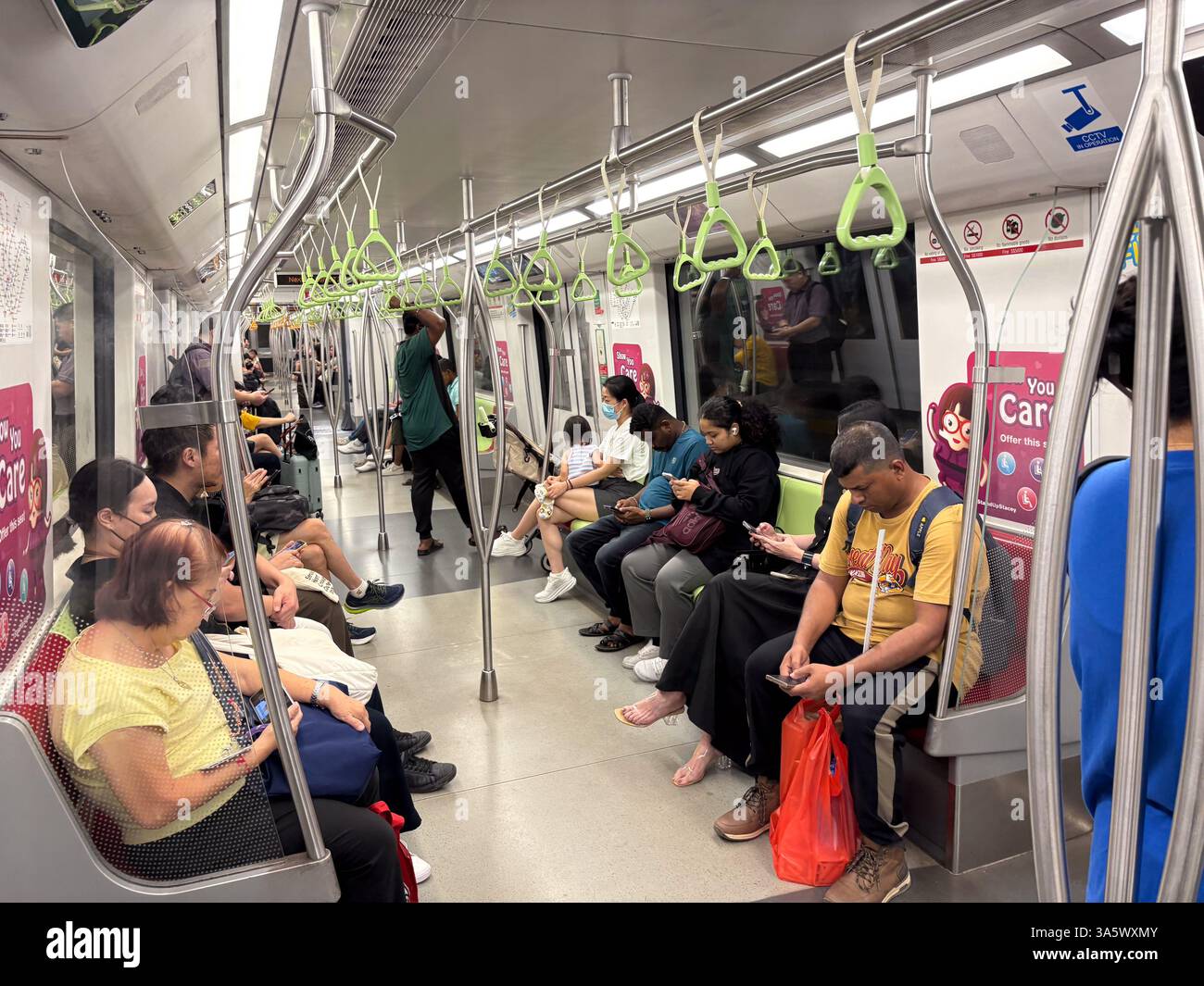The inside of a Singapore Mass Rapid Transit (MRT) train car with passengers sitting and ...