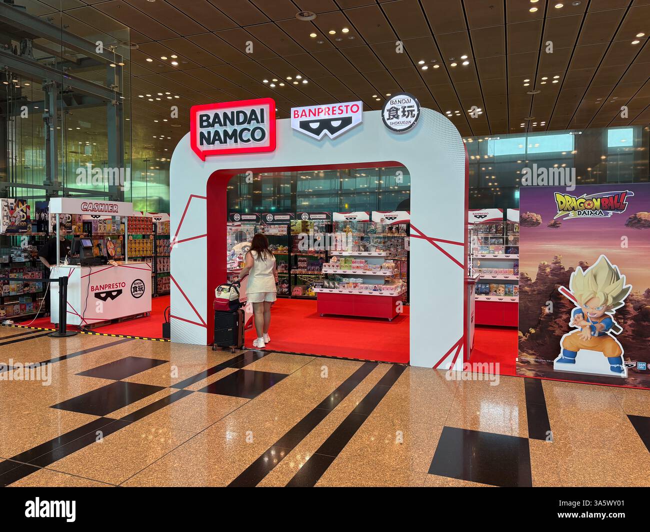 Bandai Namco store at Singapore Airport, with a female entering the store with a luggage ...