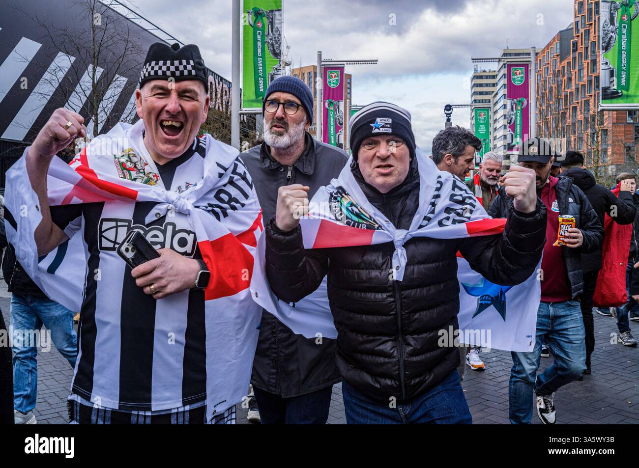 Newcastle United fans, draped in flags, pose while walking towards the ...