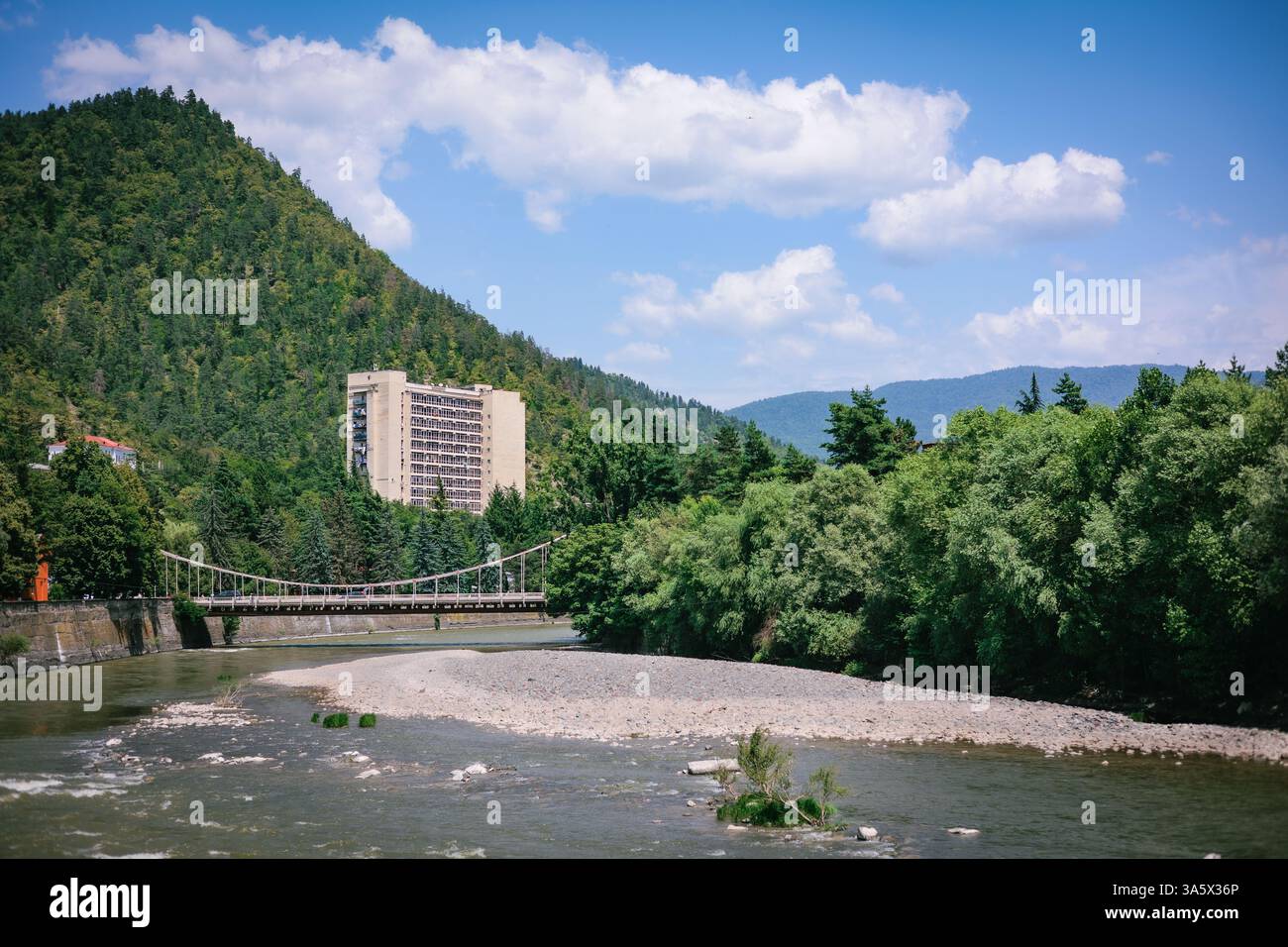 The calm River Kura flows with green tree-covered mountains in the ...