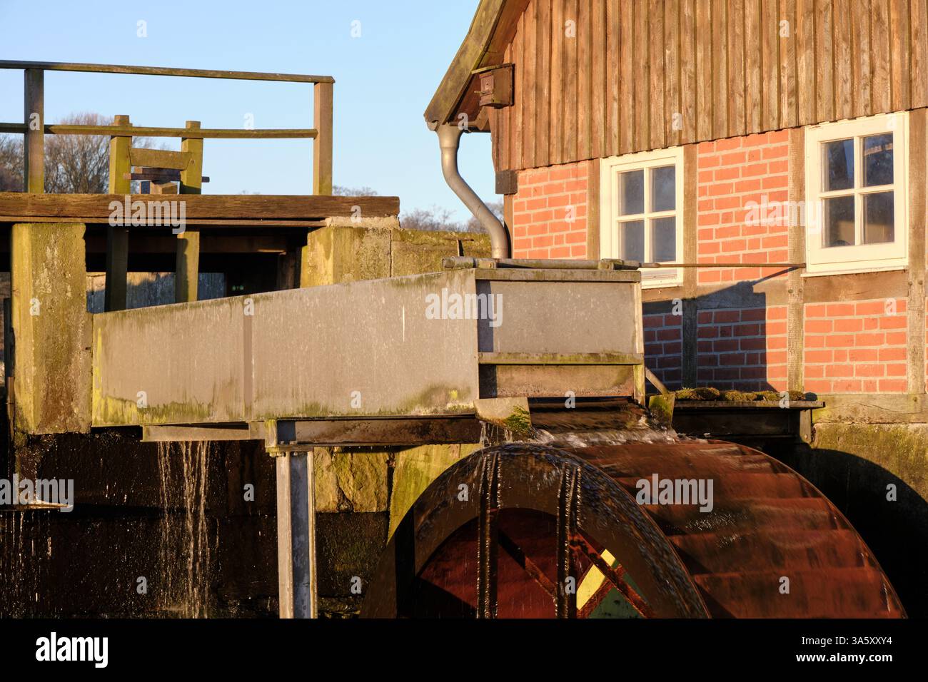 Overshot water wheel of a historic mill in morning light. Water flows ...