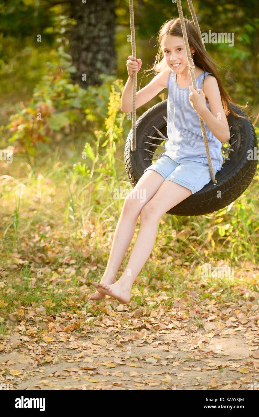 Girl swings barefoot on homemade swing made from rubber car tire ...