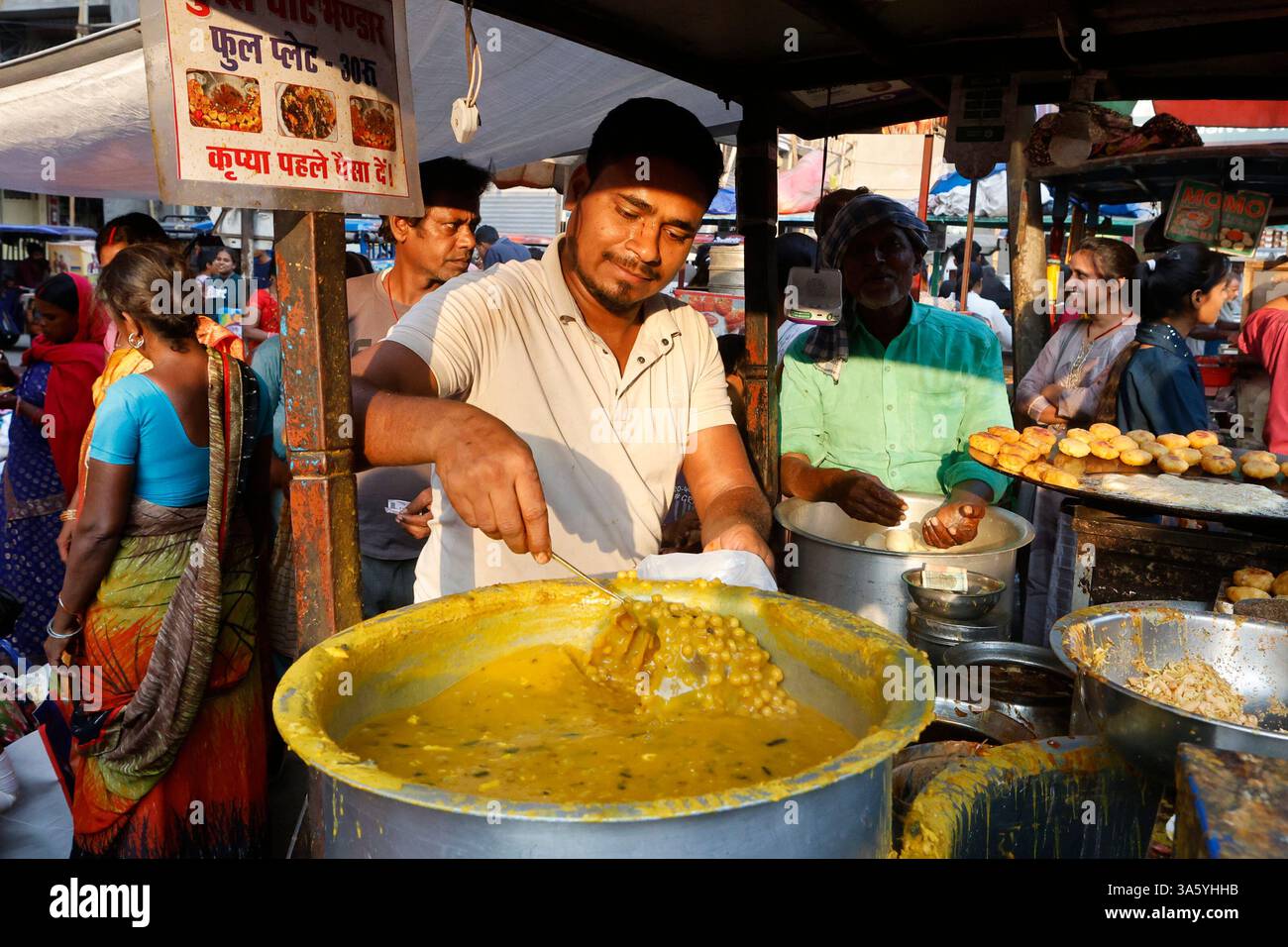 A street food vendor serving dishes of matar (chickpea) curry in Gaya ...