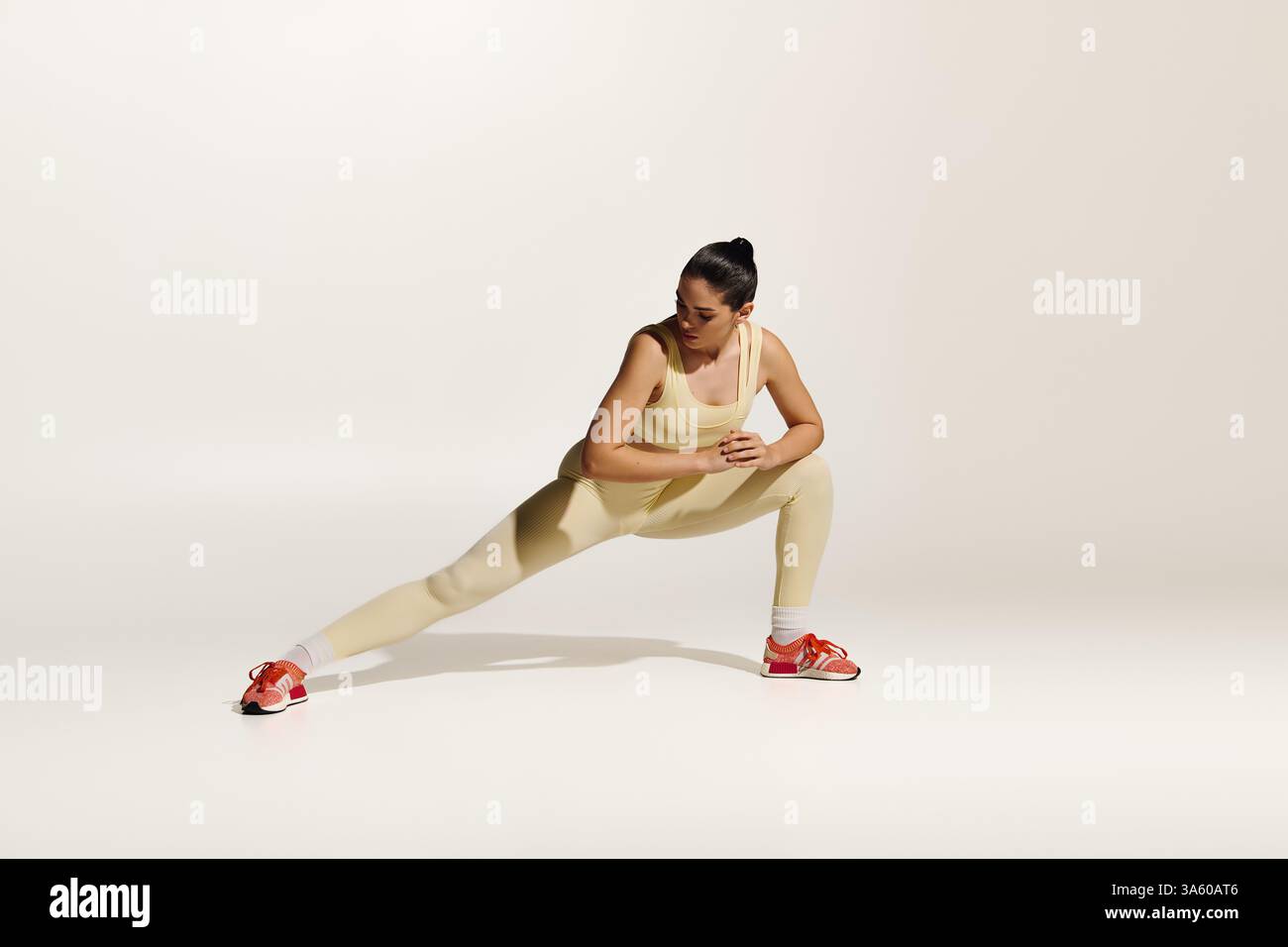 Energetic young woman performs a deep lunge stretch in a spacious ...