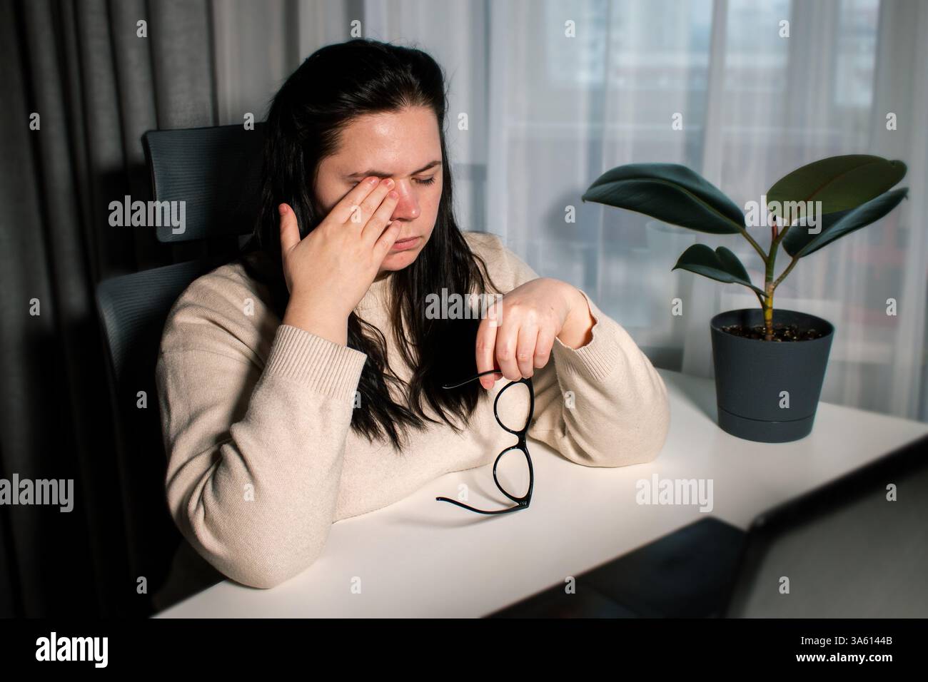 Tired woman working at home with laptop holding eyeglasses rubbing eyes ...