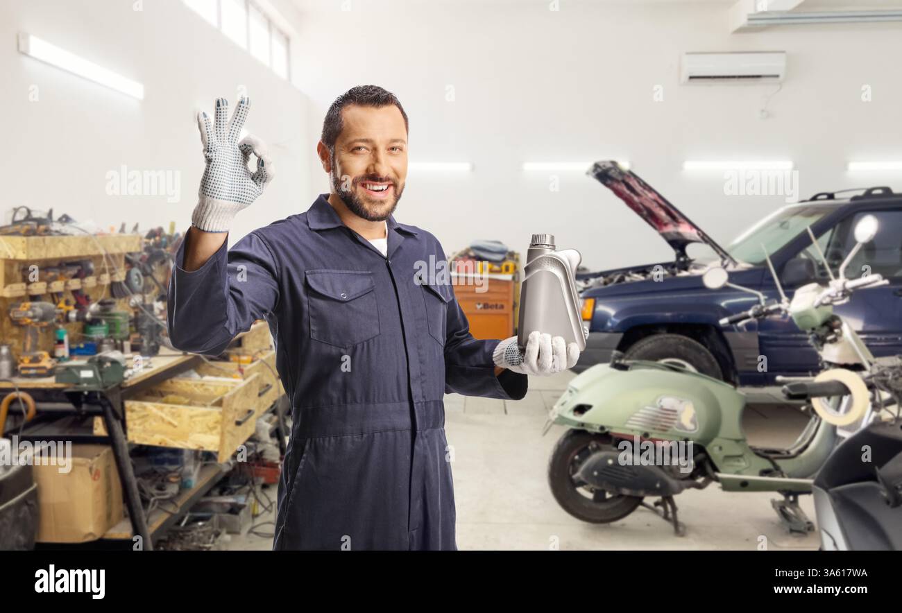 Car mechanic holding engine oil bottle and gesturing ok sign in a ...