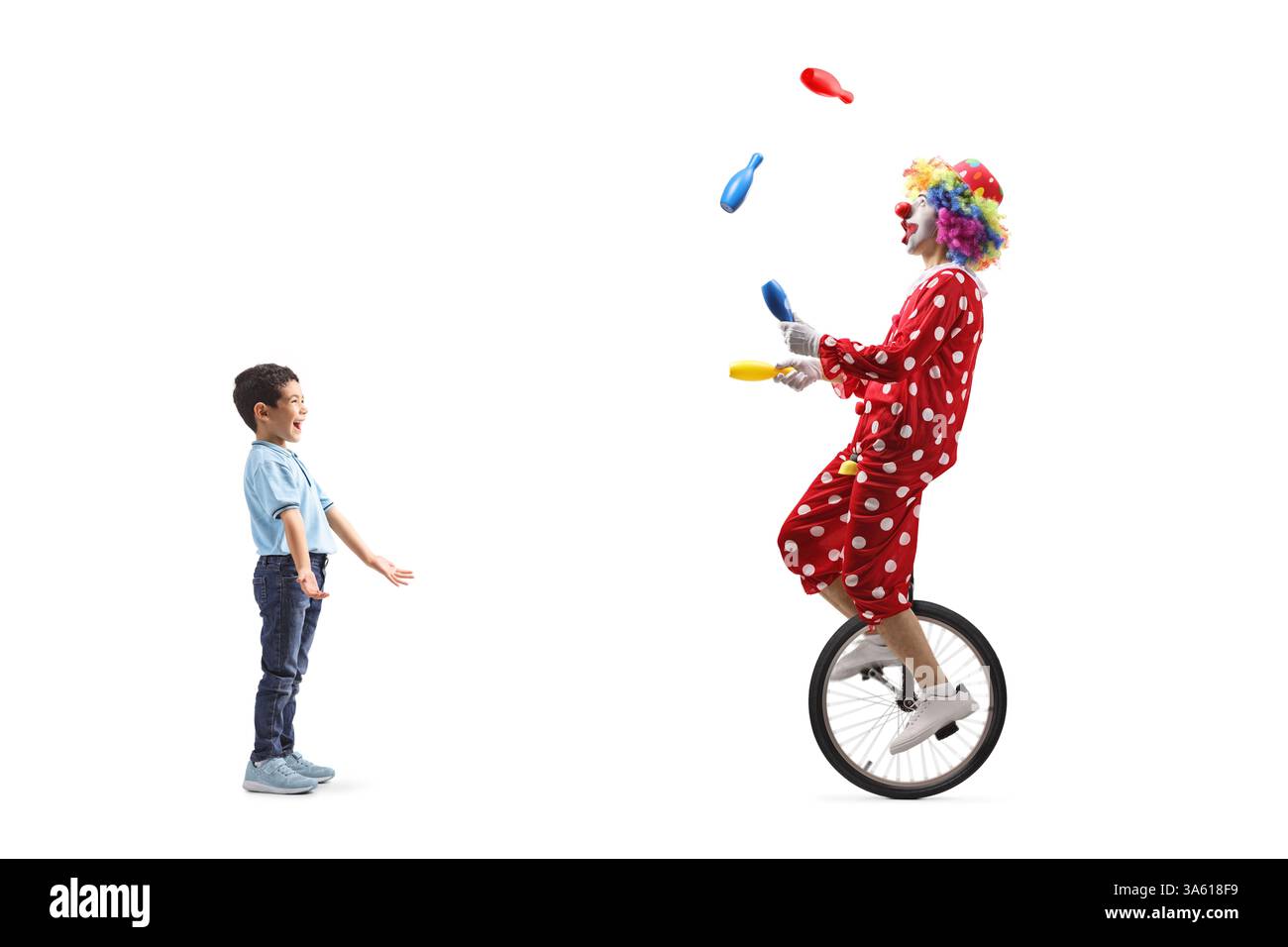 Kid watching a clown juggling on a monocycle isolated on white ...