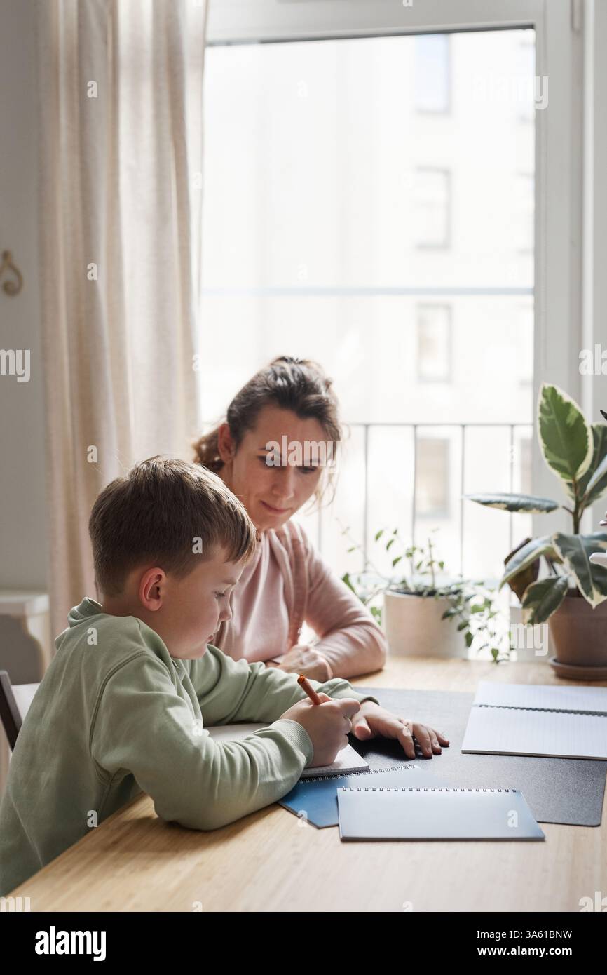Vertical side view portrait of caring single mother helping son doing ...