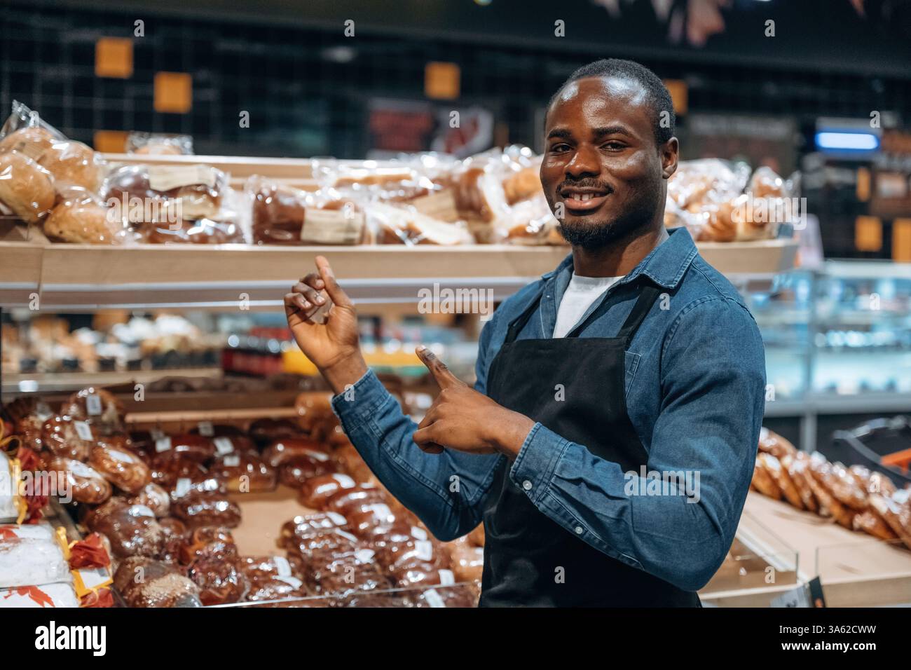 Supermarket worker is standing near bread products Stock Photo - Alamy