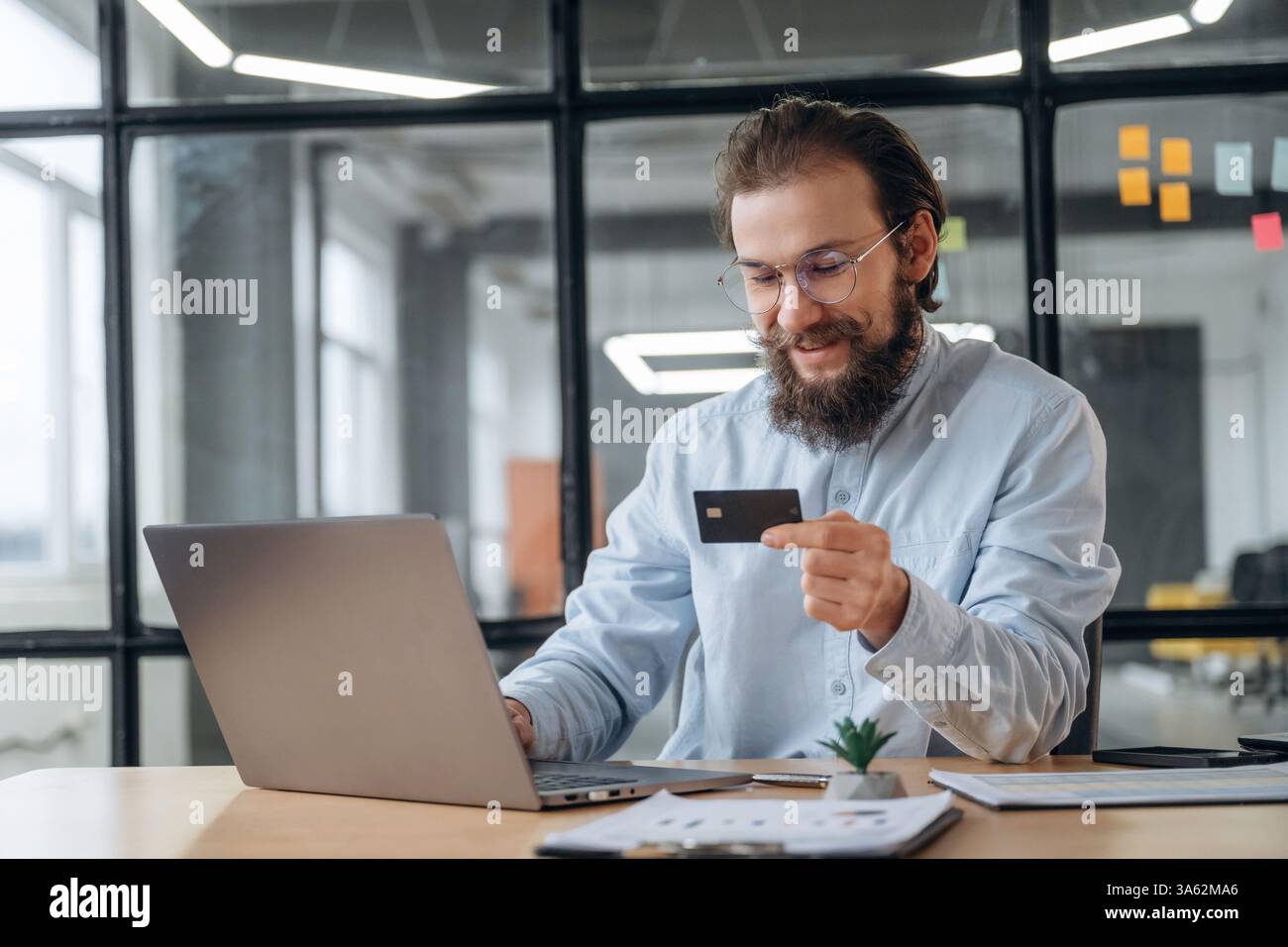 Smiling, holding credit card. Businessman is working in the office ...