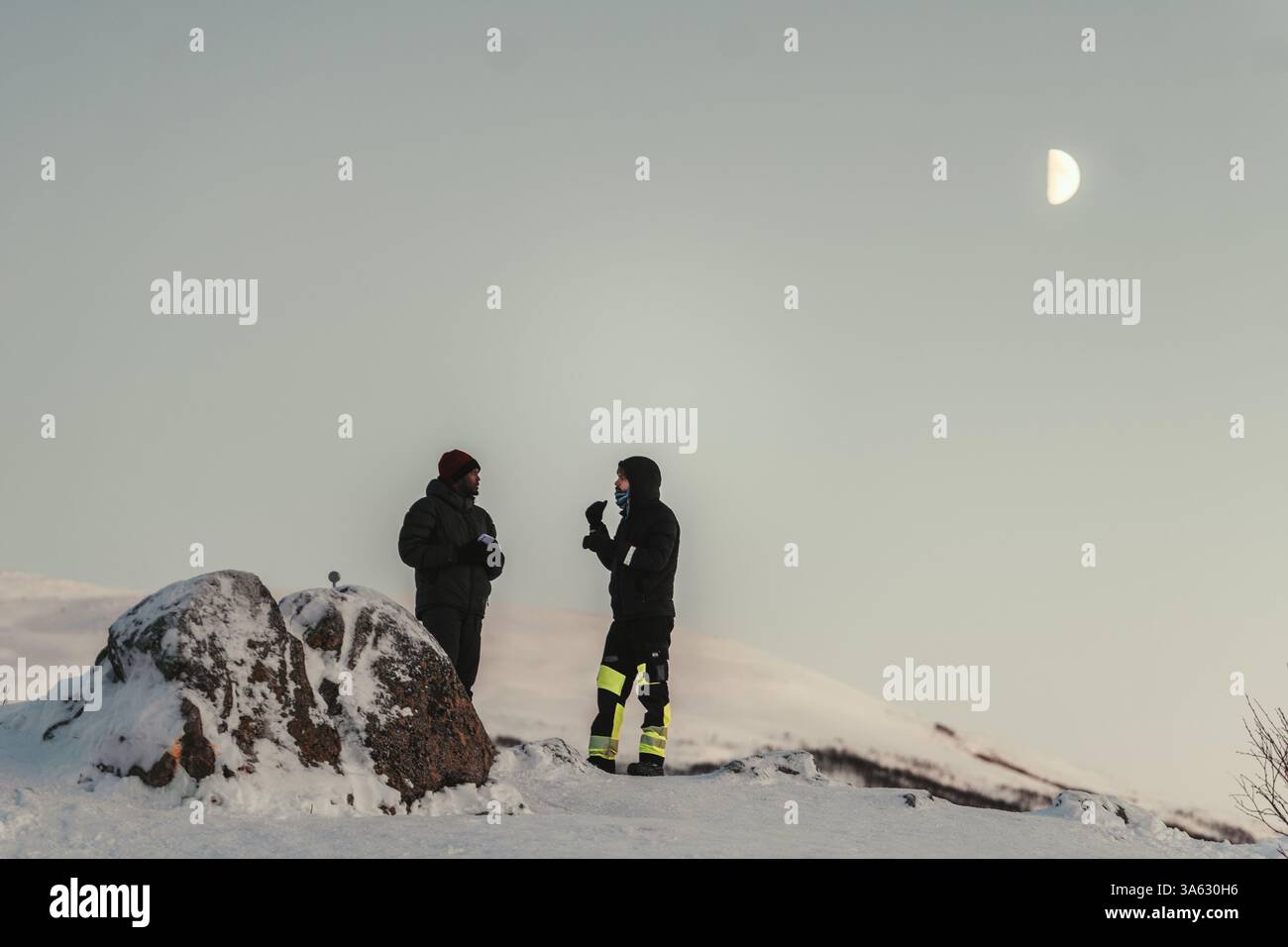 Men under moon at snowy arctic mountain viewing spot in Ersfjord ...