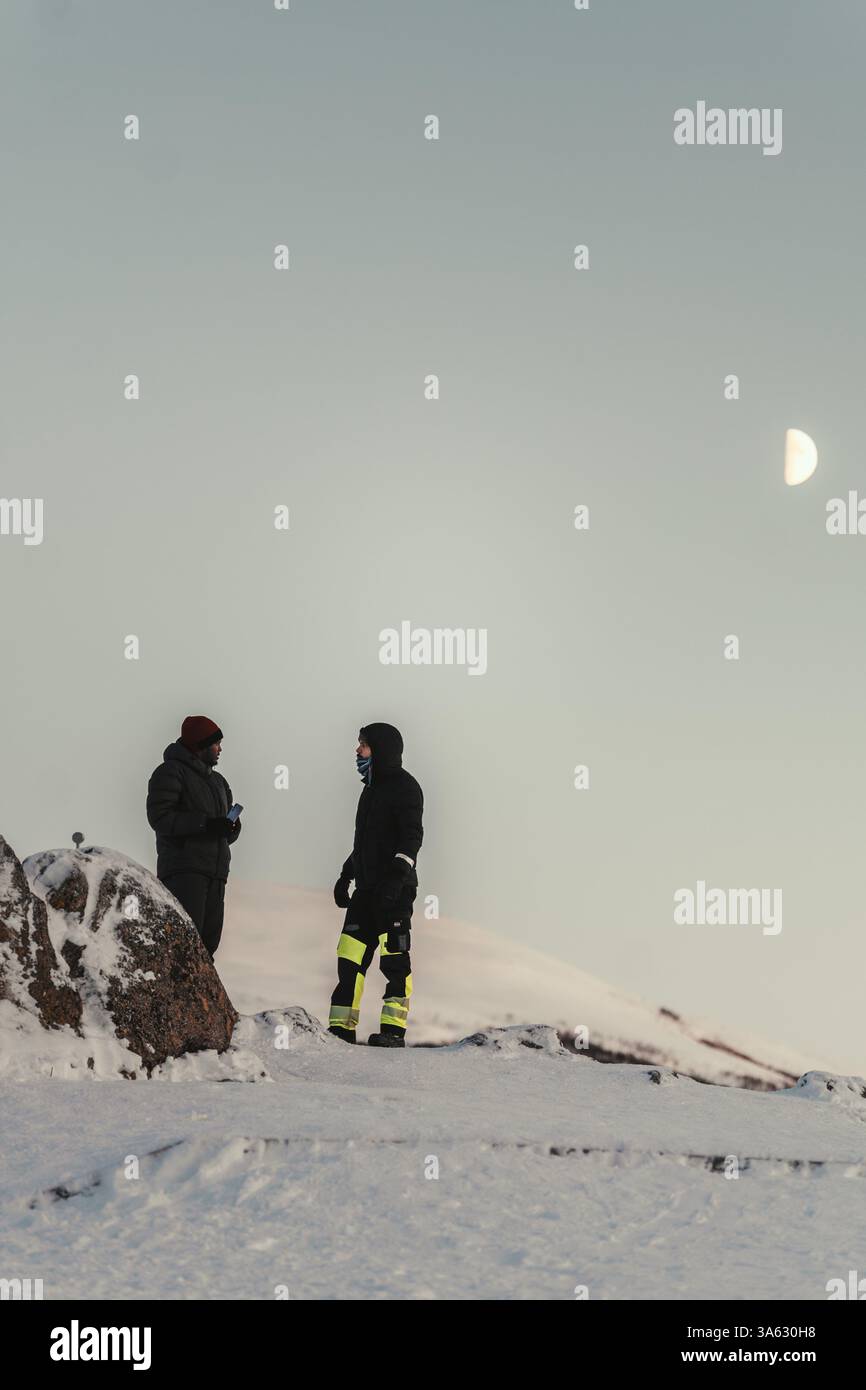 Men under moon on snowy arctic mountain viewing spot in Ersfjord Tromso ...