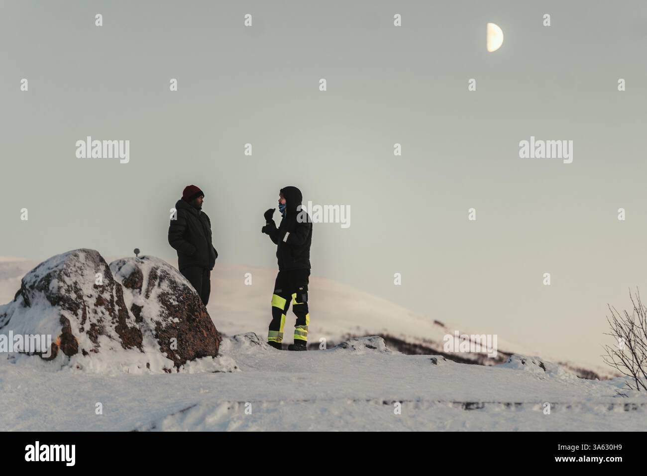 Men under moon at snowy arctic mountain viewing spot in Ersfjord Tromso ...