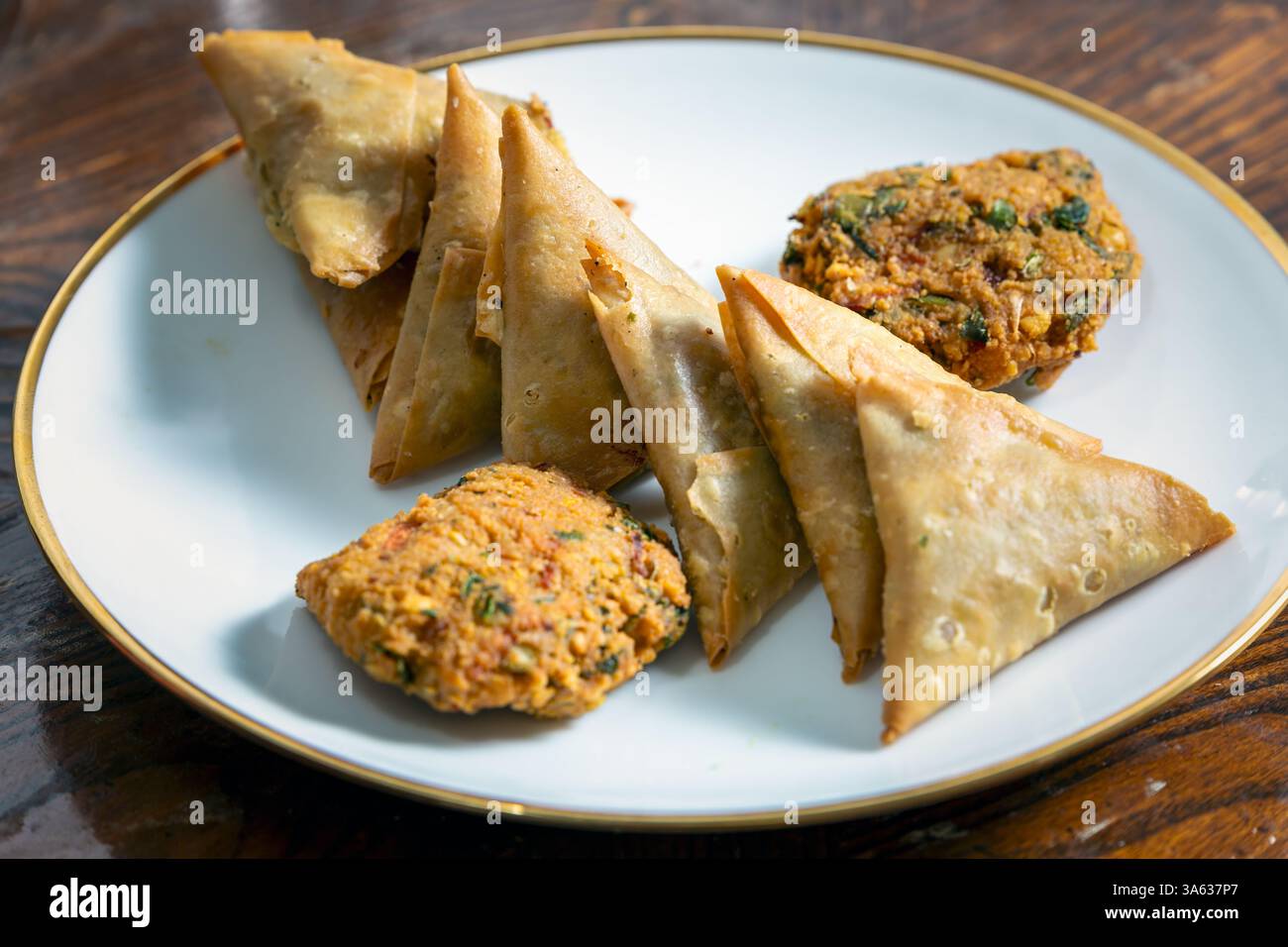 A group of Indian tea-time snacks, including samosa and vada, on a ...