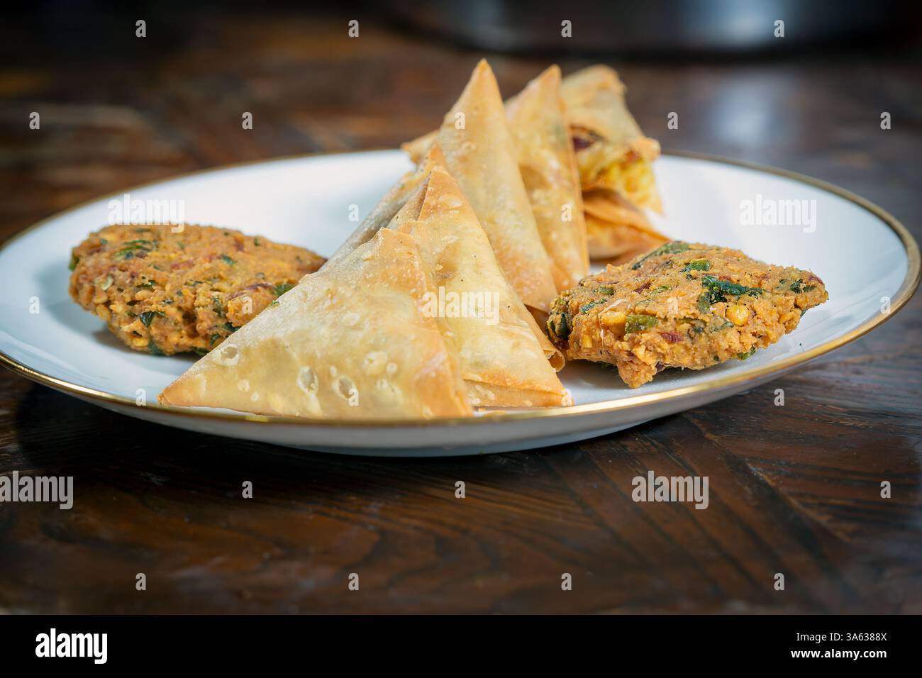 A group of Indian tea-time snacks, including samosa and vada, on a ...