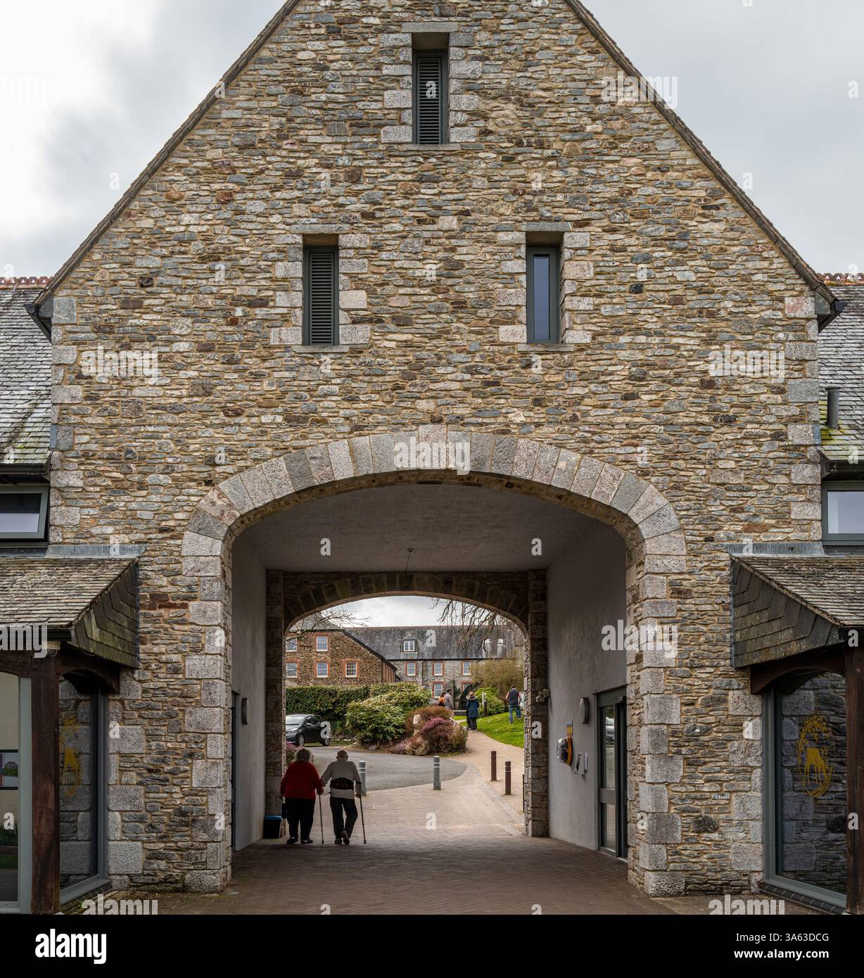 Elderly couple with walking sticks walk under an arch at Buckfast Abbey ...