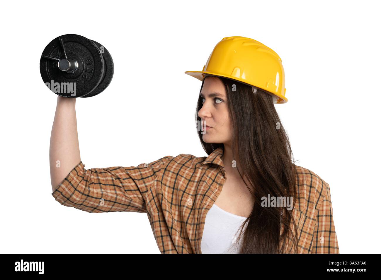 A determined female construction worker wearing a yellow hard hat lifts ...