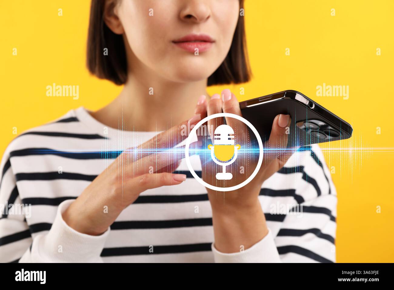 Young woman recording voice message via smartphone on yellow background ...