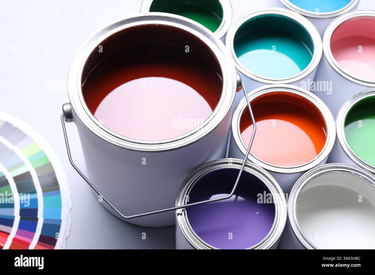 Cans of bright paints and color palettes on light background, closeup ...