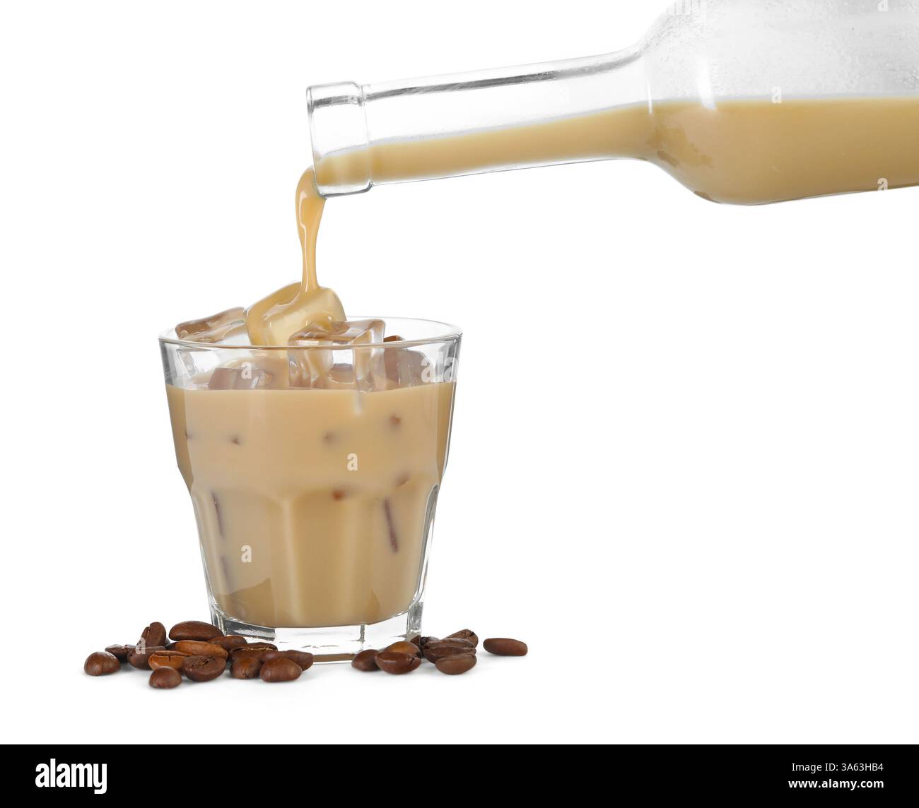 Pouring coffee cream liqueur from bottle into glass isolated on white ...