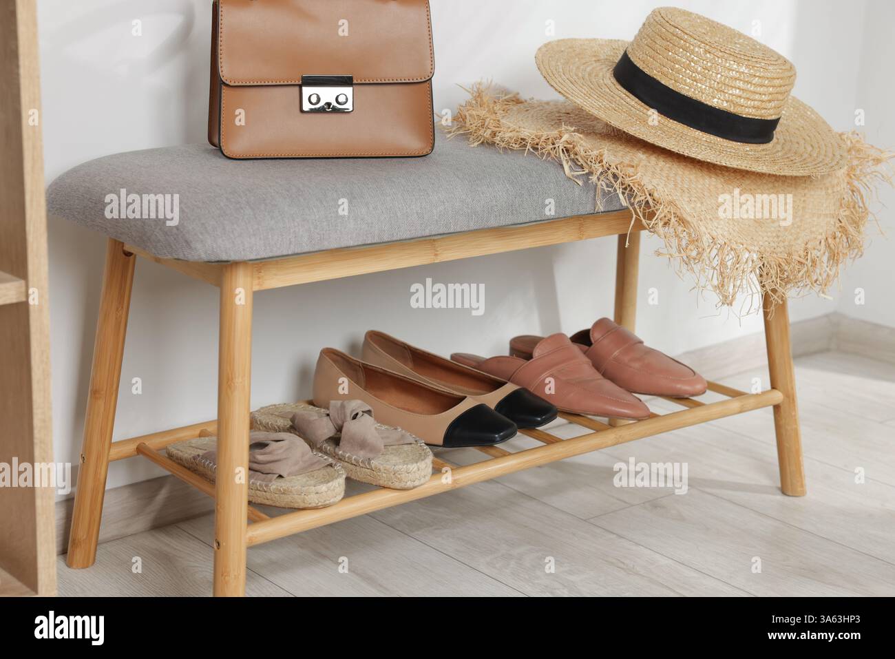 Stand with different stylish shoes, straw hats and bag indoors Stock ...