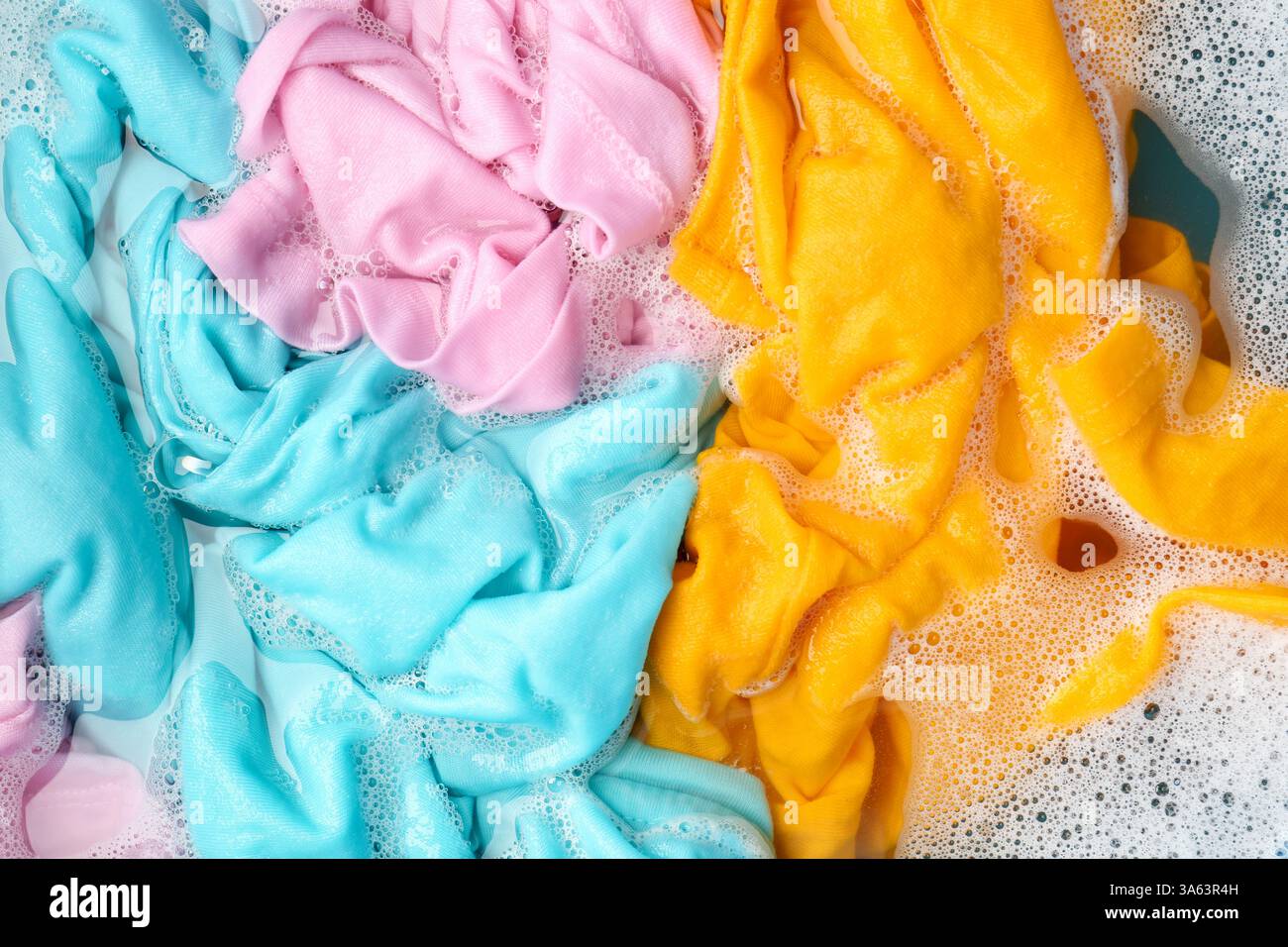 Colorful clothes soaked in water before washing, top view Stock Photo ...