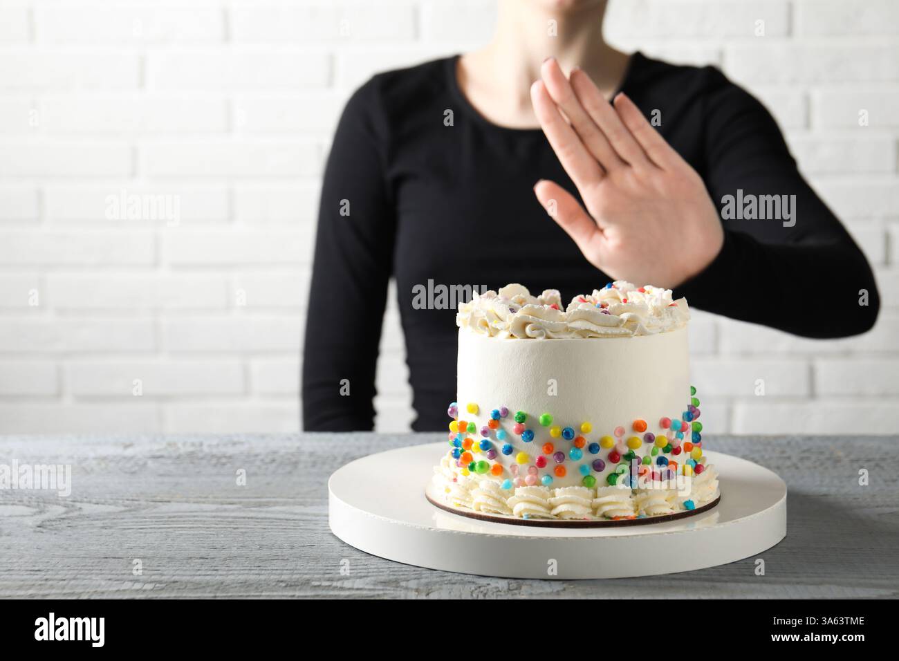 Food allergy concept. Woman refusing to eat cake at grey wooden table ...