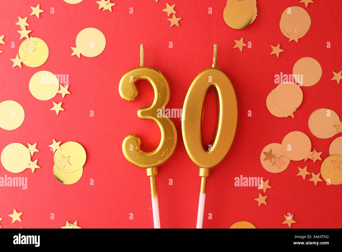30th birthday. Number shaped candles and confetti on red background ...