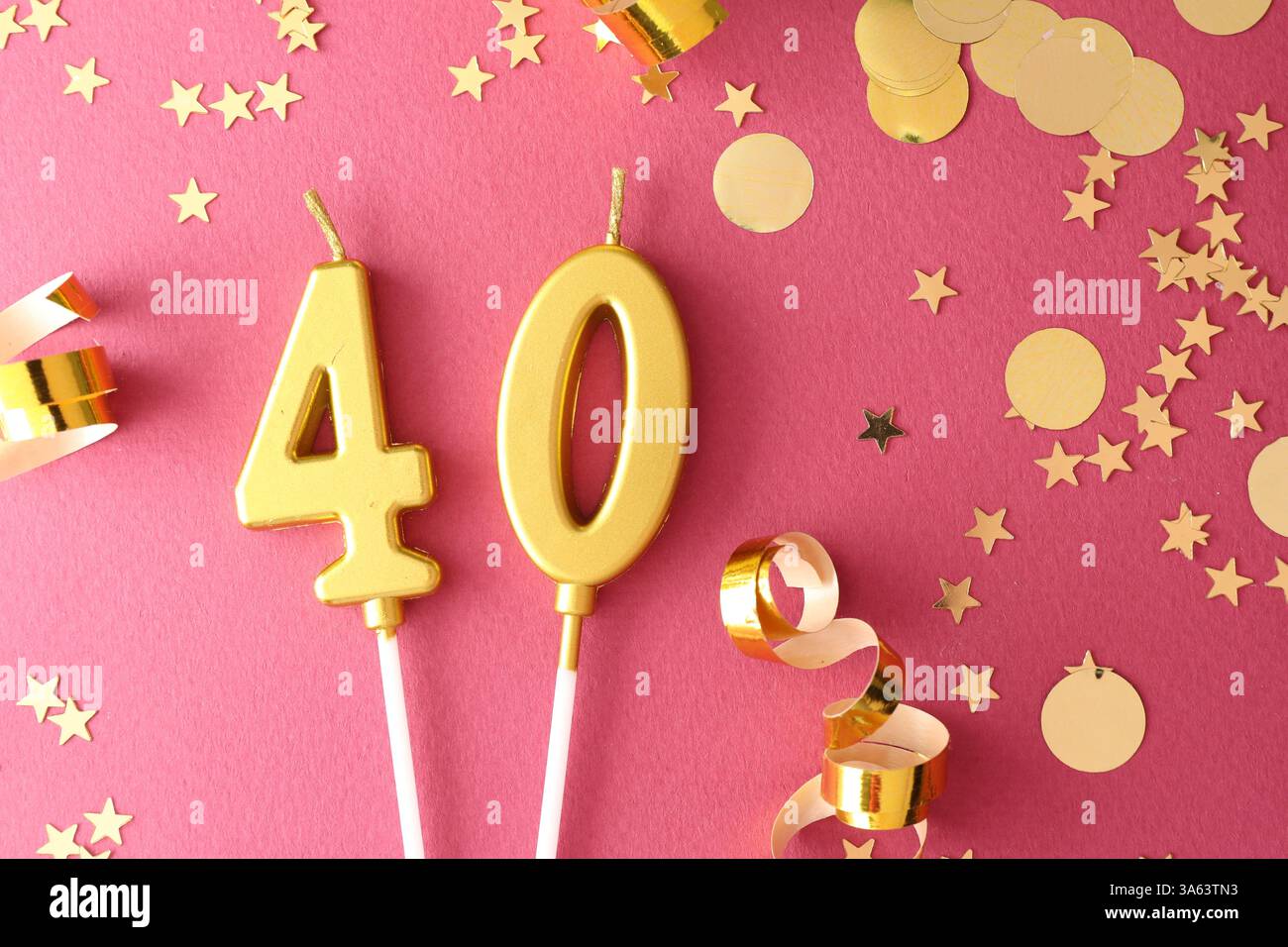 40th birthday. Number shaped candles and confetti on pink background ...