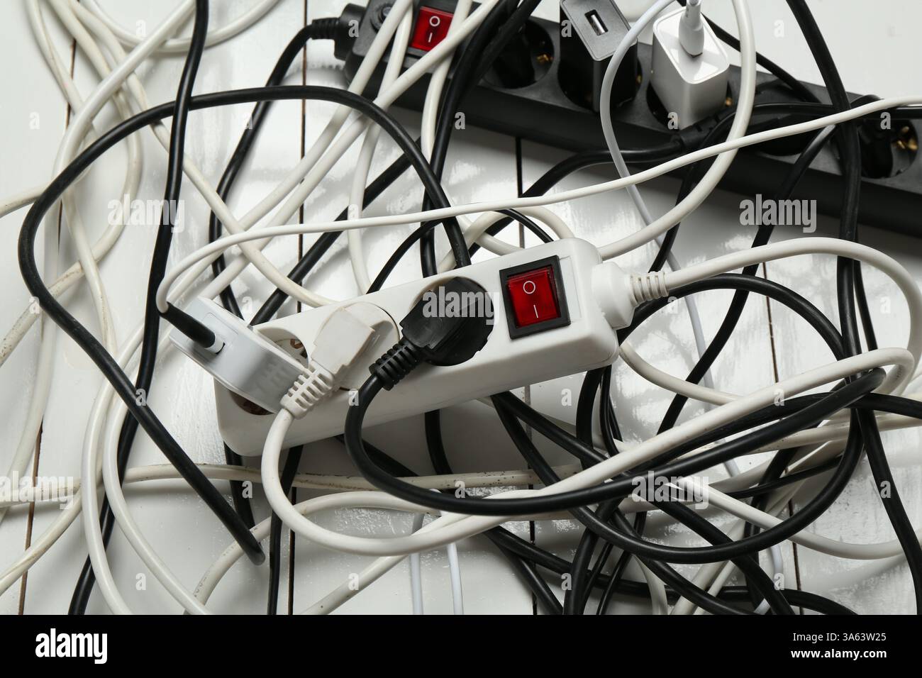 Extension power boards overloaded with plugs on wooden floor, closeup ...