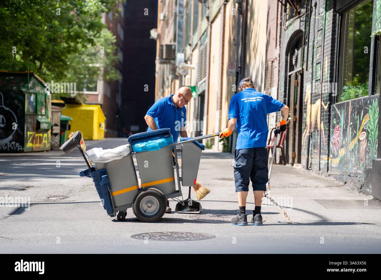 MONTREAL, CANADA - JULY 18, 2024: Two sanitation workers in blue ...