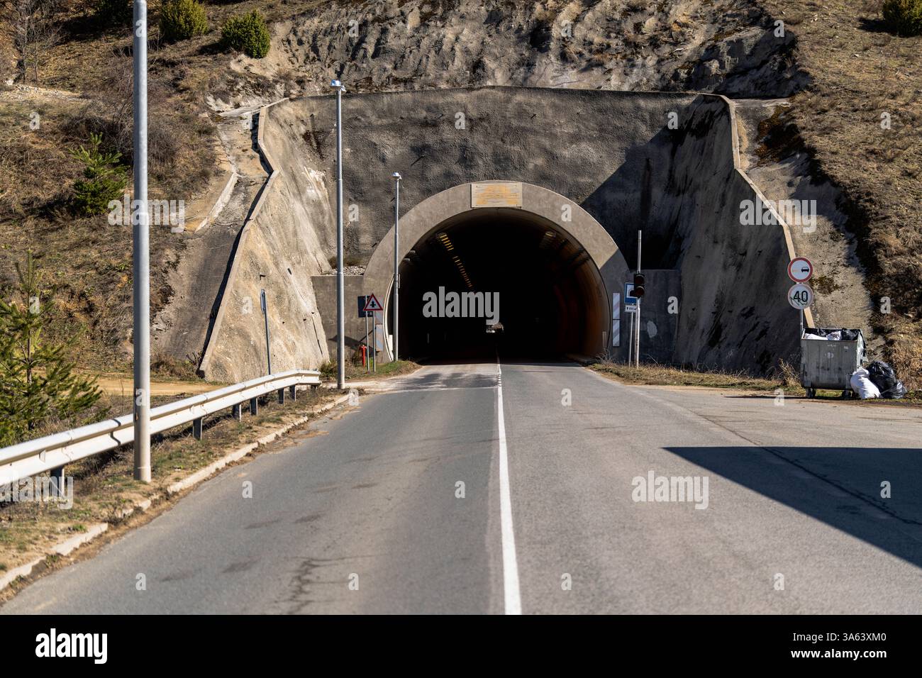 Asphalt road leading into a dark tunnel entrance crossing a mountain ...