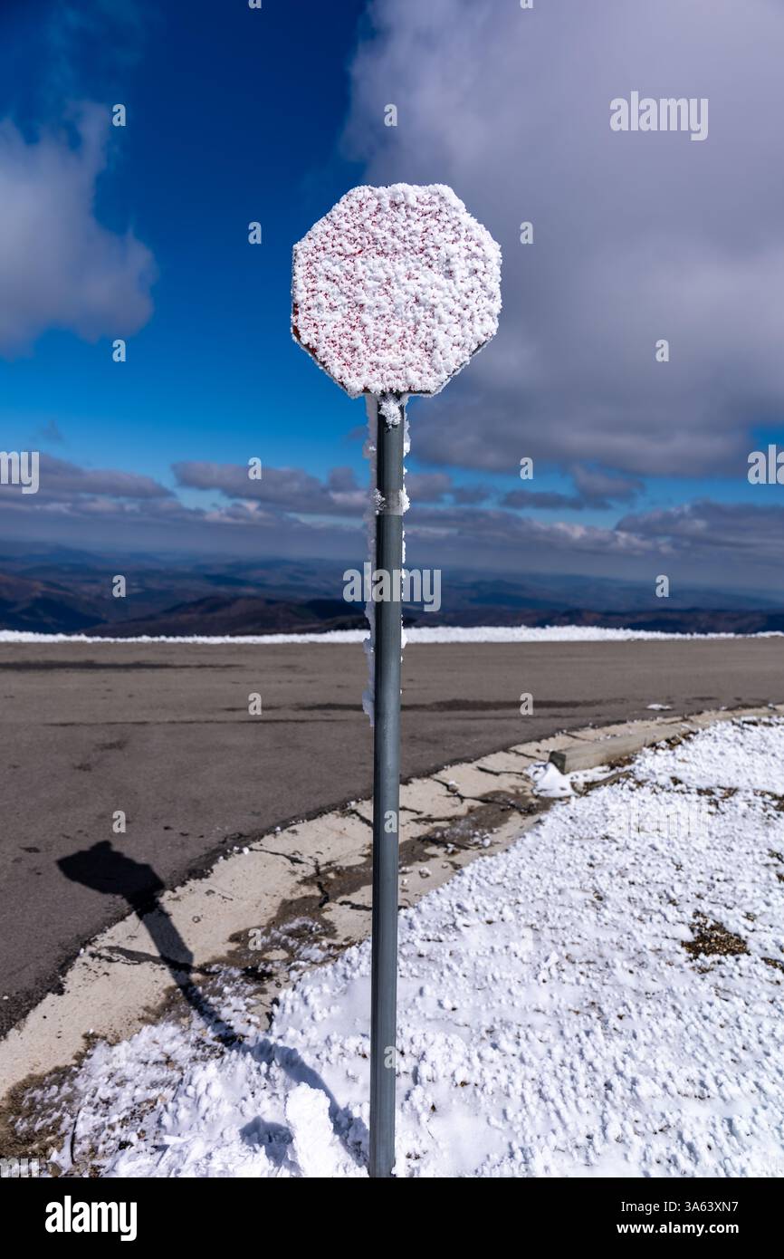 Stop sign indicating mandatory stop covered by snow on mountain road ...