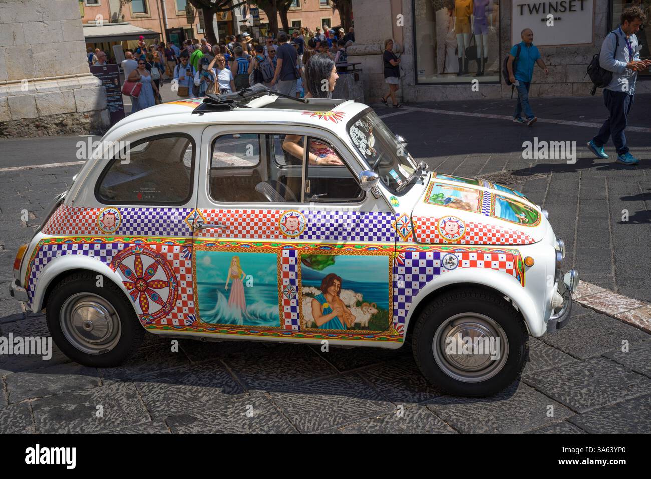 Compact car embellished with pictures and patterns on a street in ...