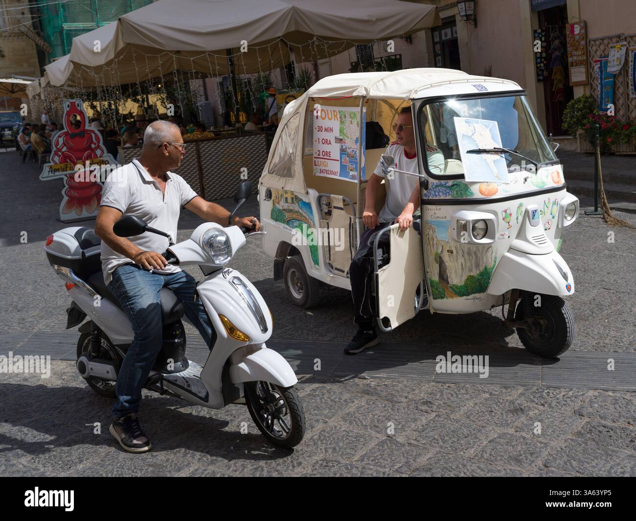 View of one man on a scooter and another man in a tuk tuk vehicle ...