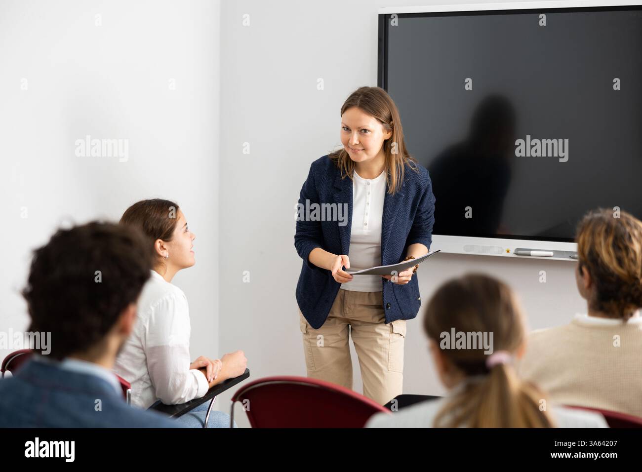 Knowledgeable female professor explaining subject to classroom full of ...