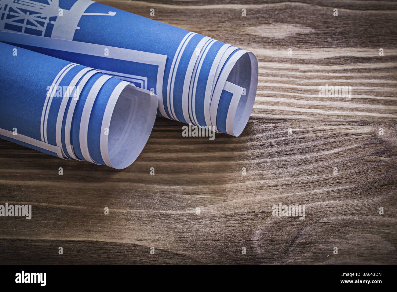 Blue rolled engineering drawings on wooden board construction concept ...