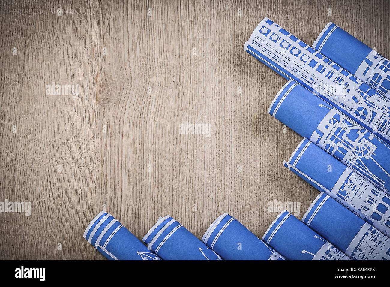 Pile of blue rolled engineering drawings on wooden board construction ...