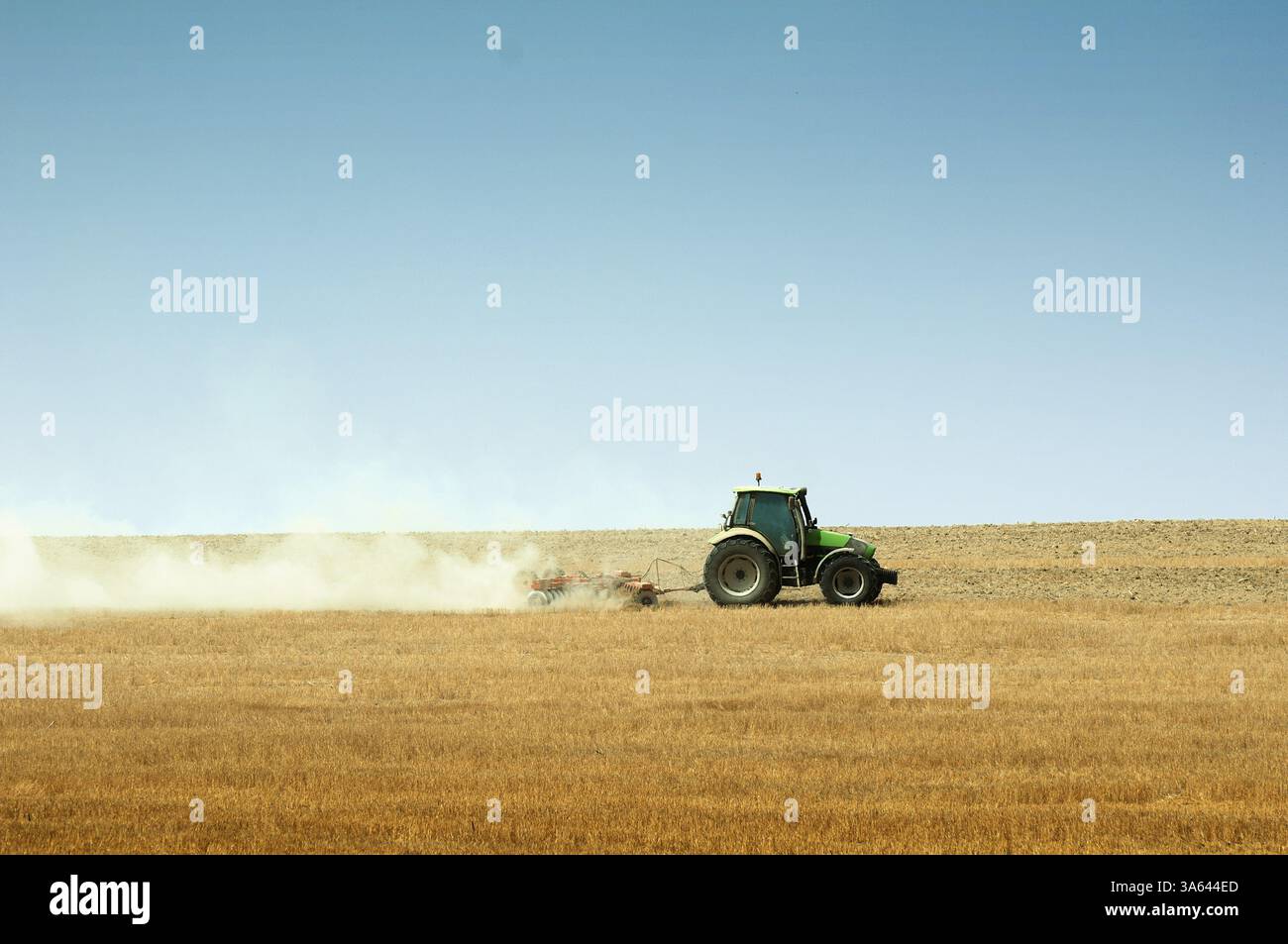 Tractor plowing field on blue sky background Stock Photo - Alamy
