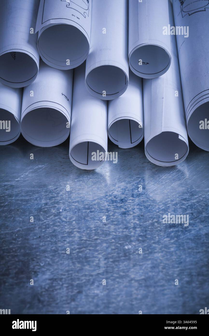 Pile of rolled engineering drawings on scratched silver-metal ...