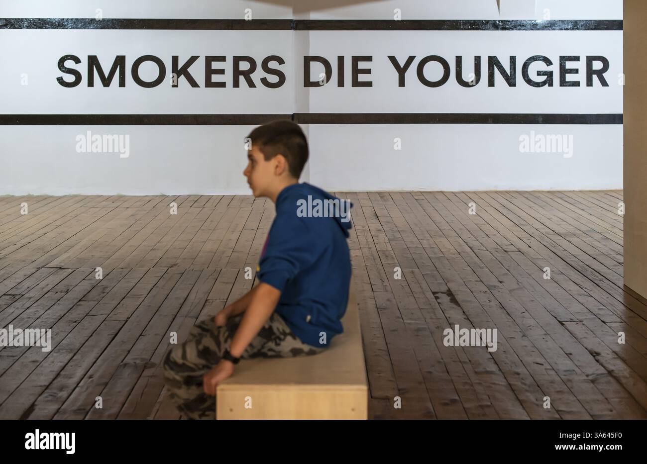 Teenager smoking and message on wall - Smokers die younger. No smoking ...